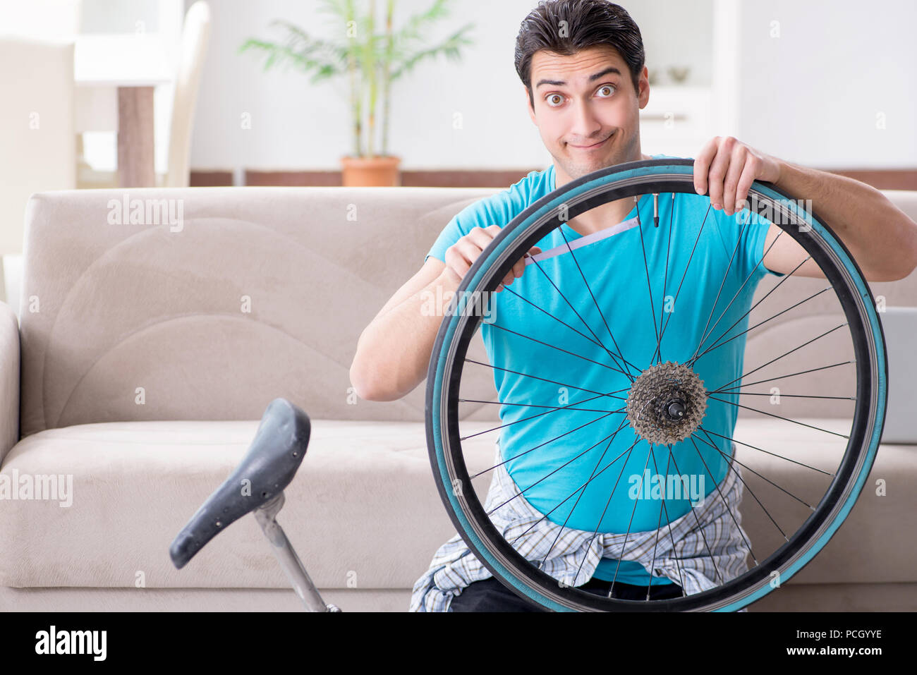 Young man repairing bicycle at home Stock Photo - Alamy