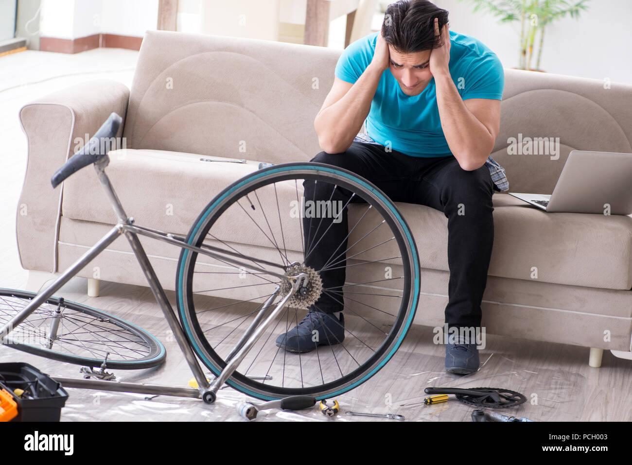 Young man repairing bicycle at home Stock Photo - Alamy