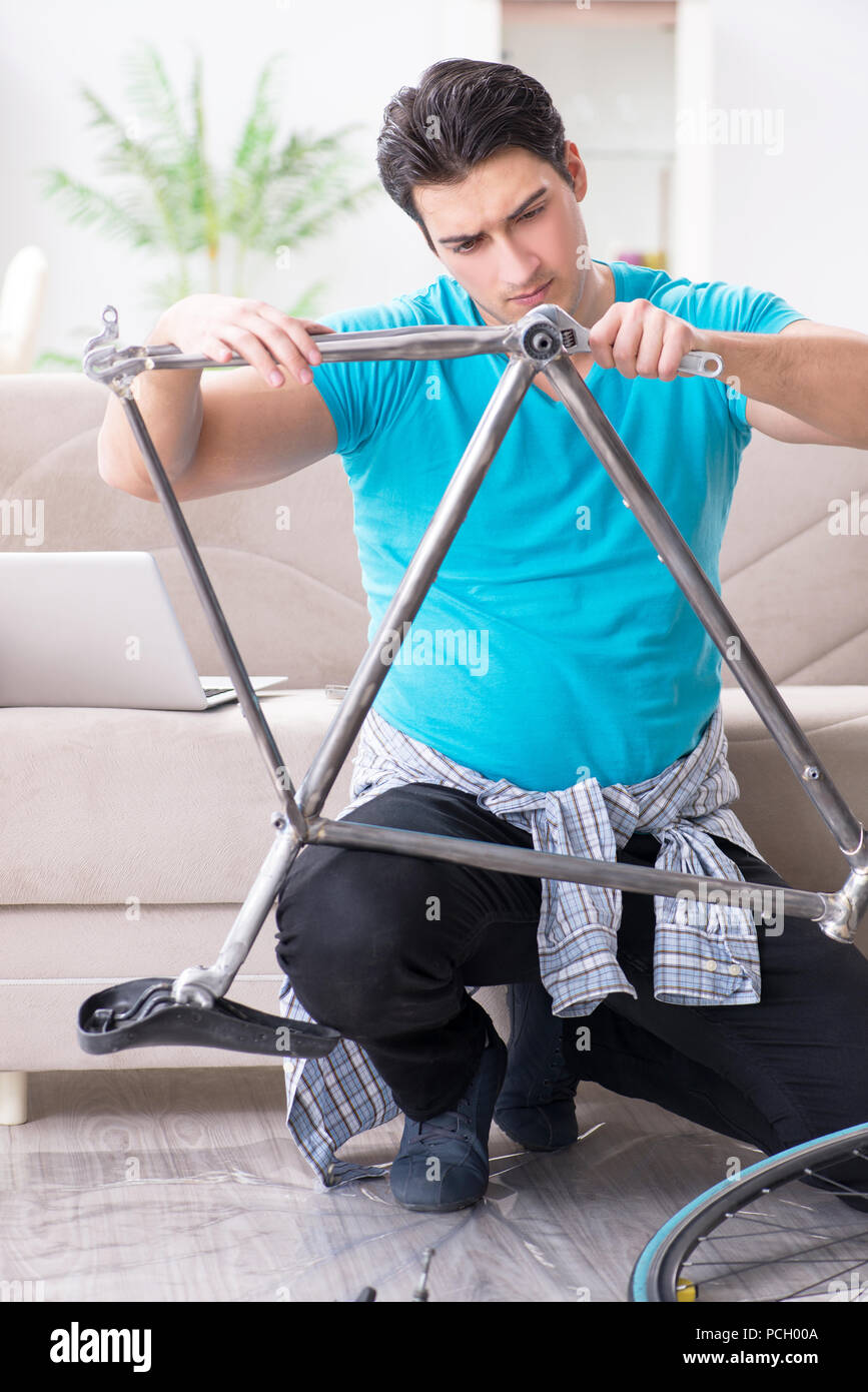 Young man repairing bicycle at home Stock Photo - Alamy