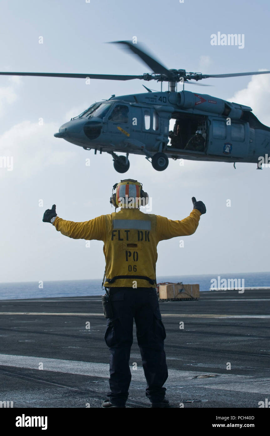 A U.S. Navy aircraft director signals to an MH-60S Knight Hawk with ...
