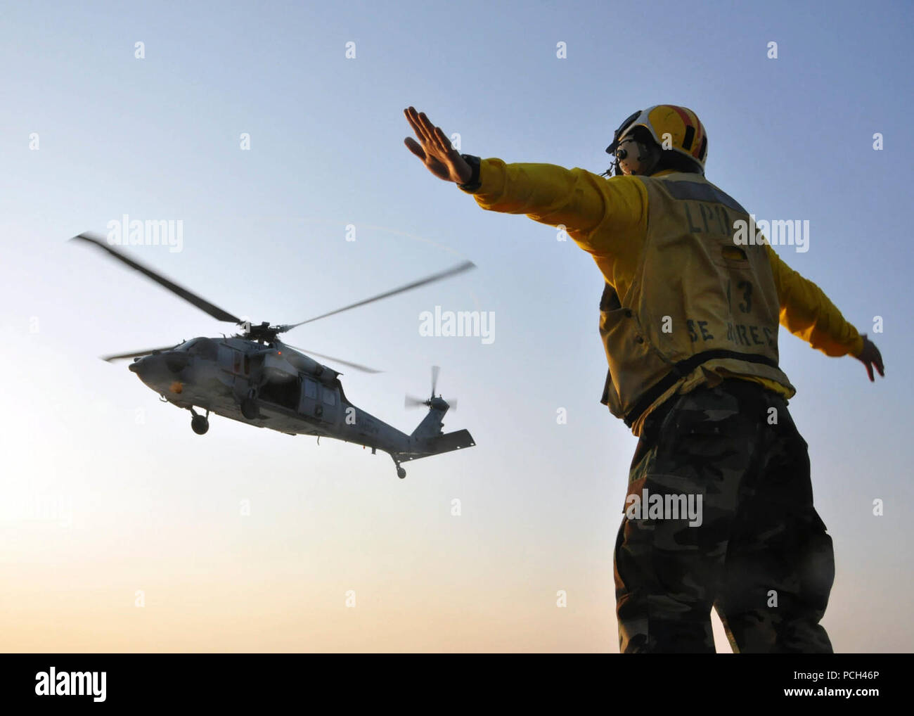 A U.S. Sailor signals to an MH-60 Seahawk helicopter pilot assigned to ...