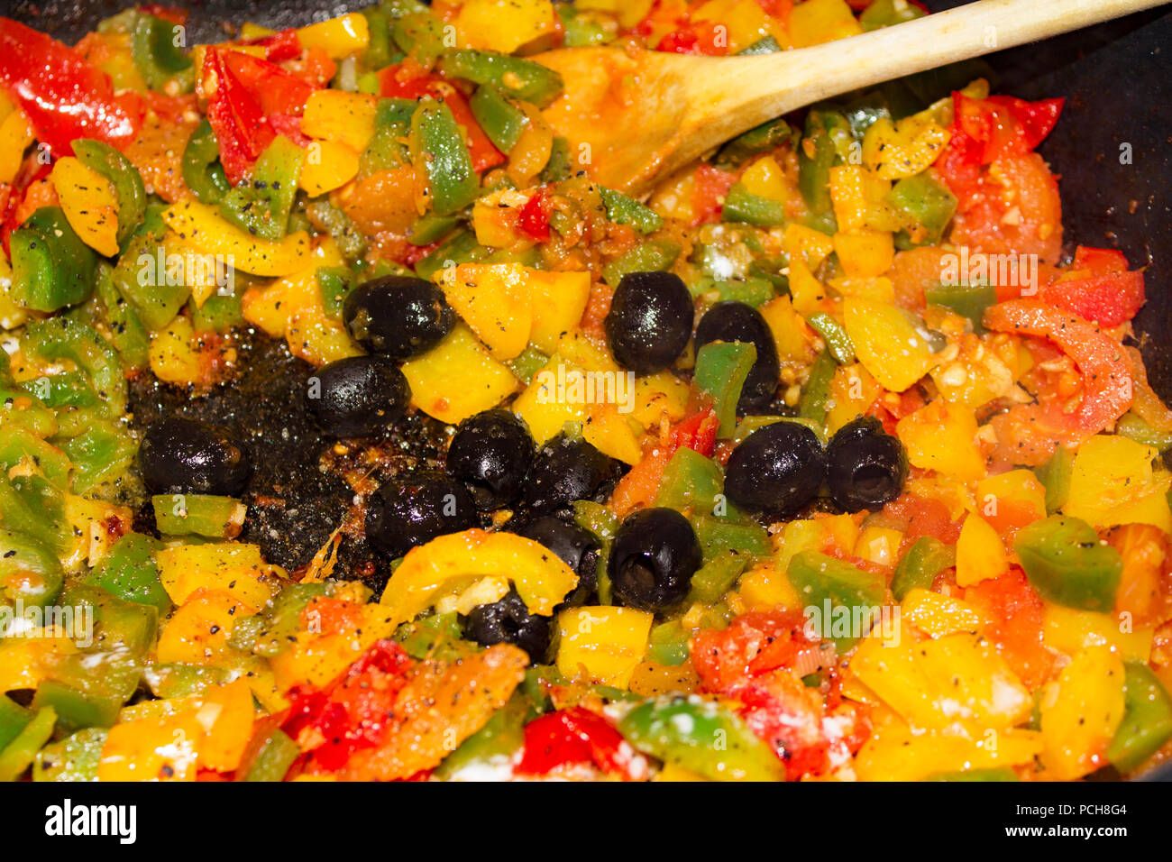 Cooking a tasty colorful vegetable stir fry with peppers and olives in ...