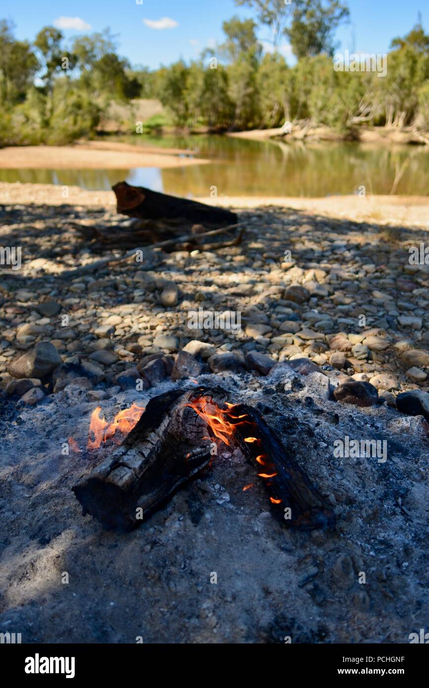 An Australian bush camp fire on rocks next to a creek burning in the ...