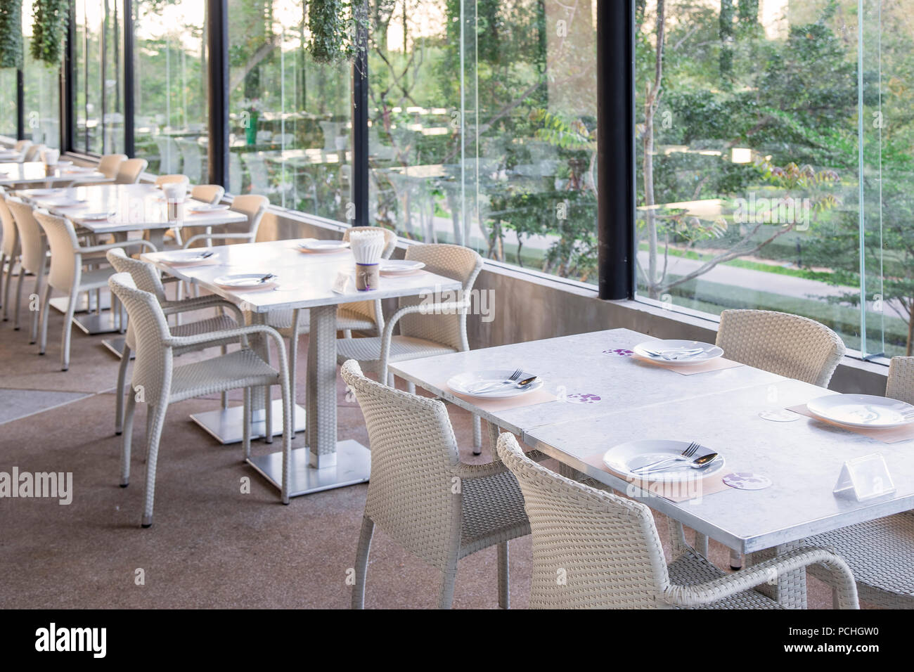Restaurant table setting by the window with view garden Stock Photo - Alamy