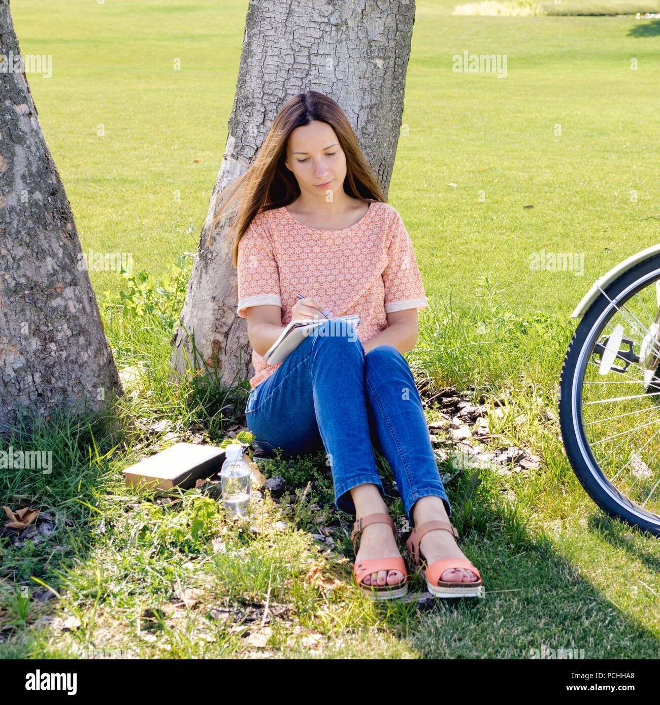 Girl sitting under tree reading hi-res stock photography and images - Alamy