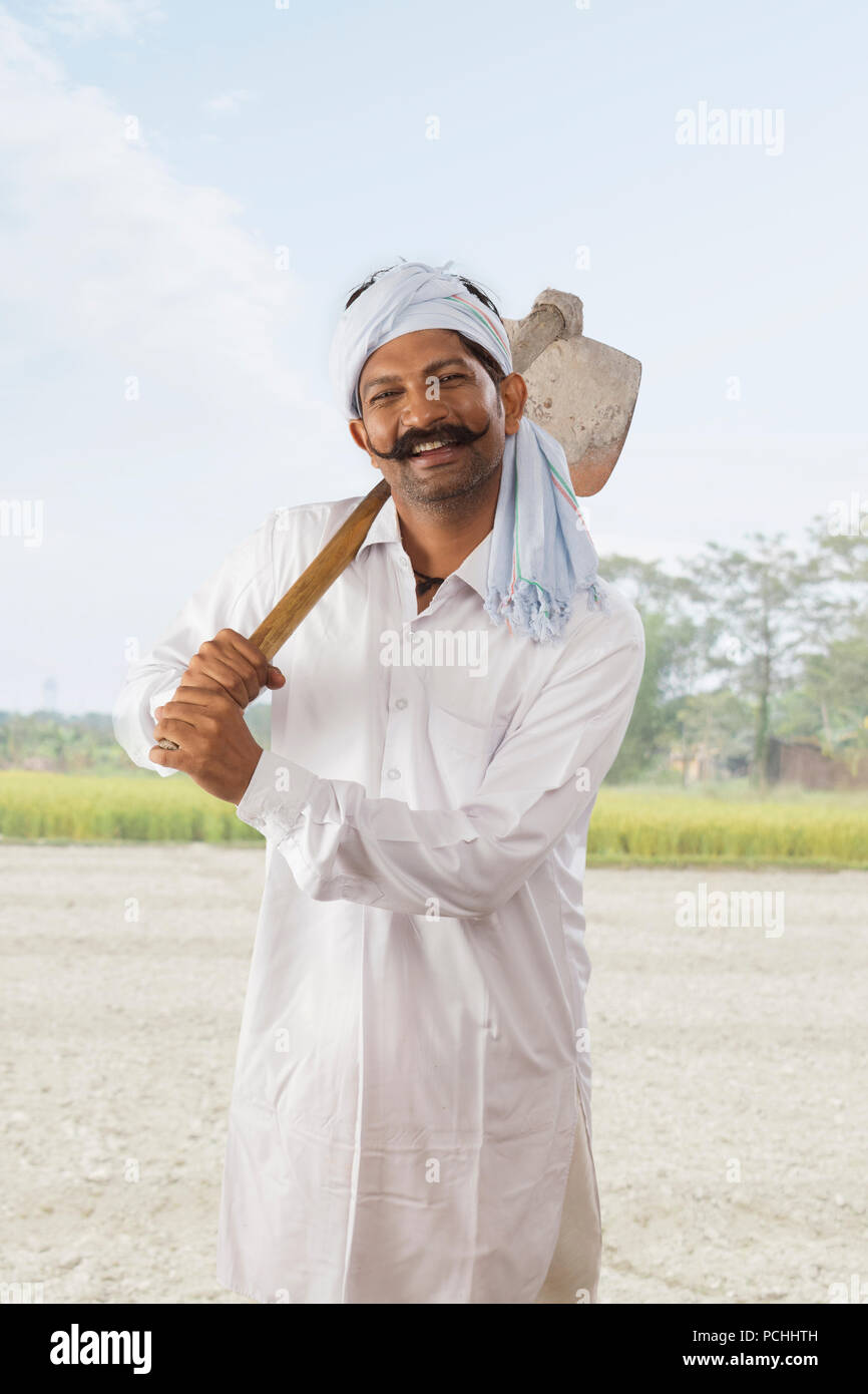 Farmer carrying hoe on his shoulder standing in field Stock Photo - Alamy