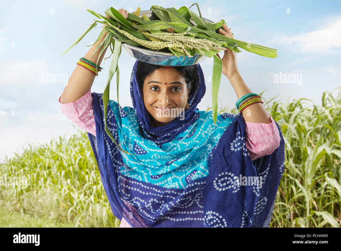 Rural woman carries corn leaves and rice on her head Stock Photo - Alamy