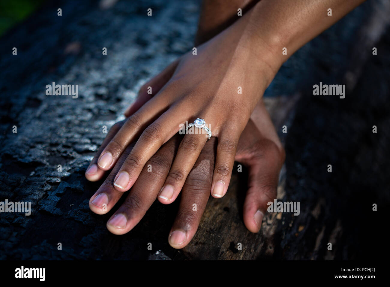 Two hands, one wearing an engagement ring Stock Photo - Alamy