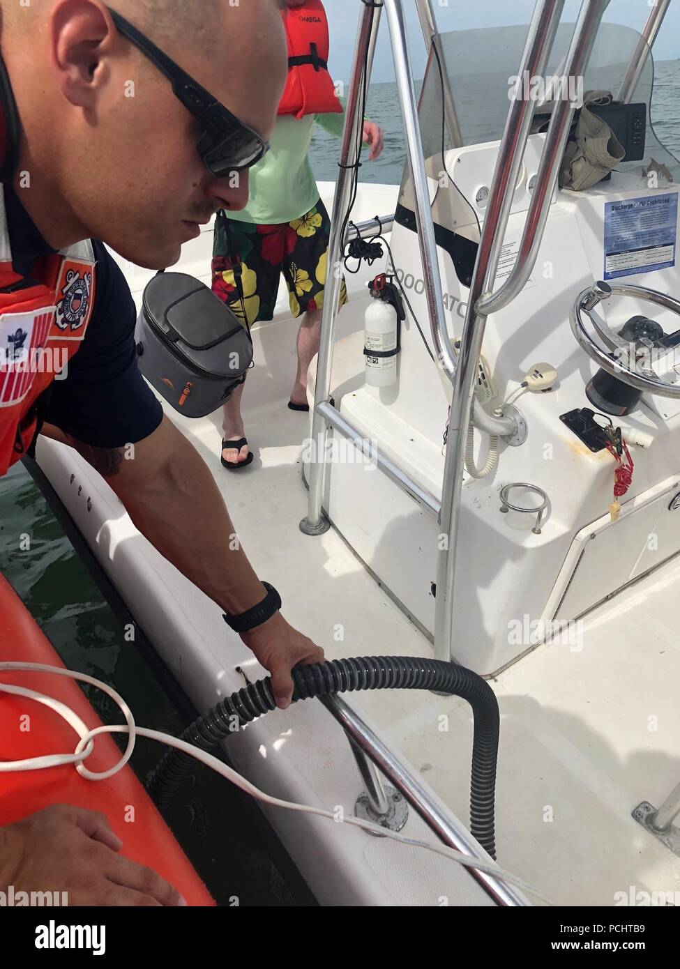Petty Officer 3rd Class Chase Cook helps a boater dewater a 20-foot ...