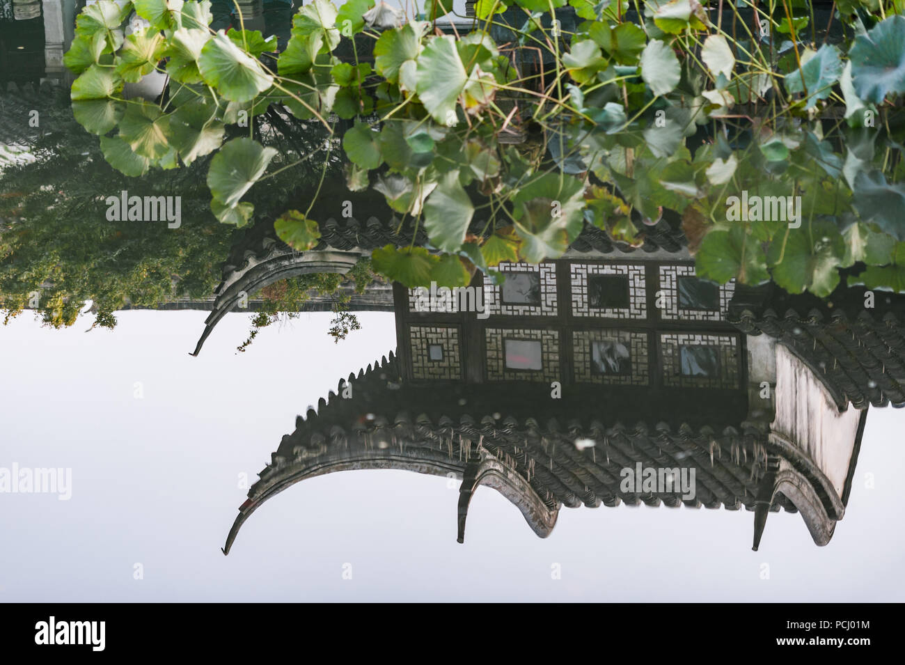 Traditional garden roofs reflected in a pond in Suzhou, China ...