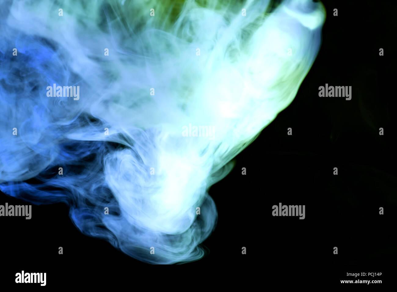 Thick colorful blue, green and yellow smoke on a black isolated ...