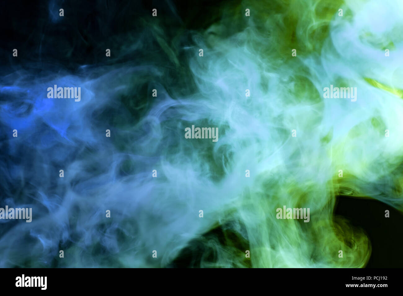 Dense multicolored smoke of blue and green colors on a black isolated ...