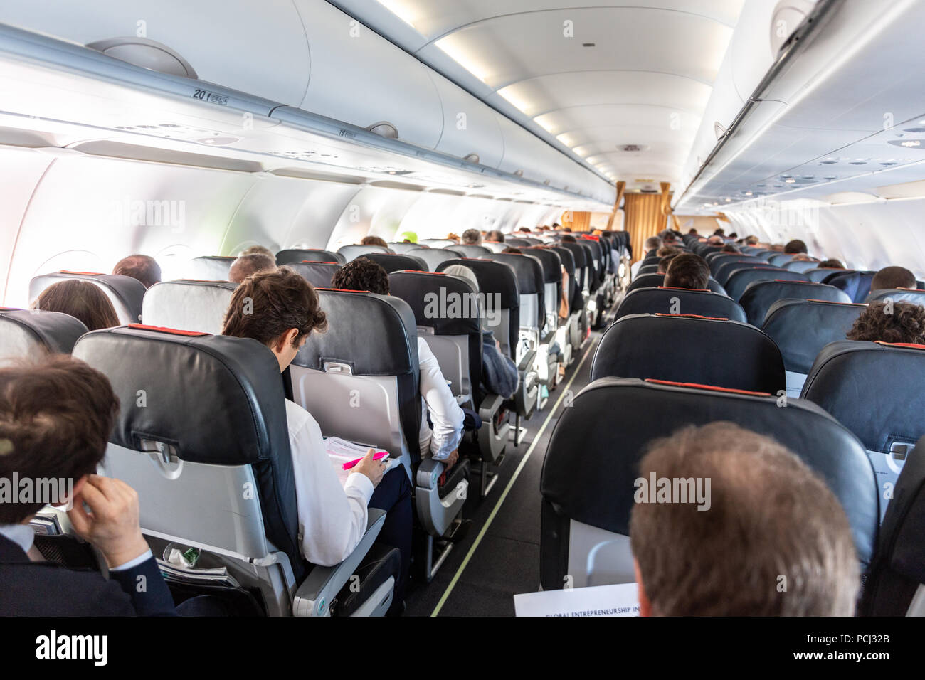 Interior of large commercial airplane with passengers on their seats ...