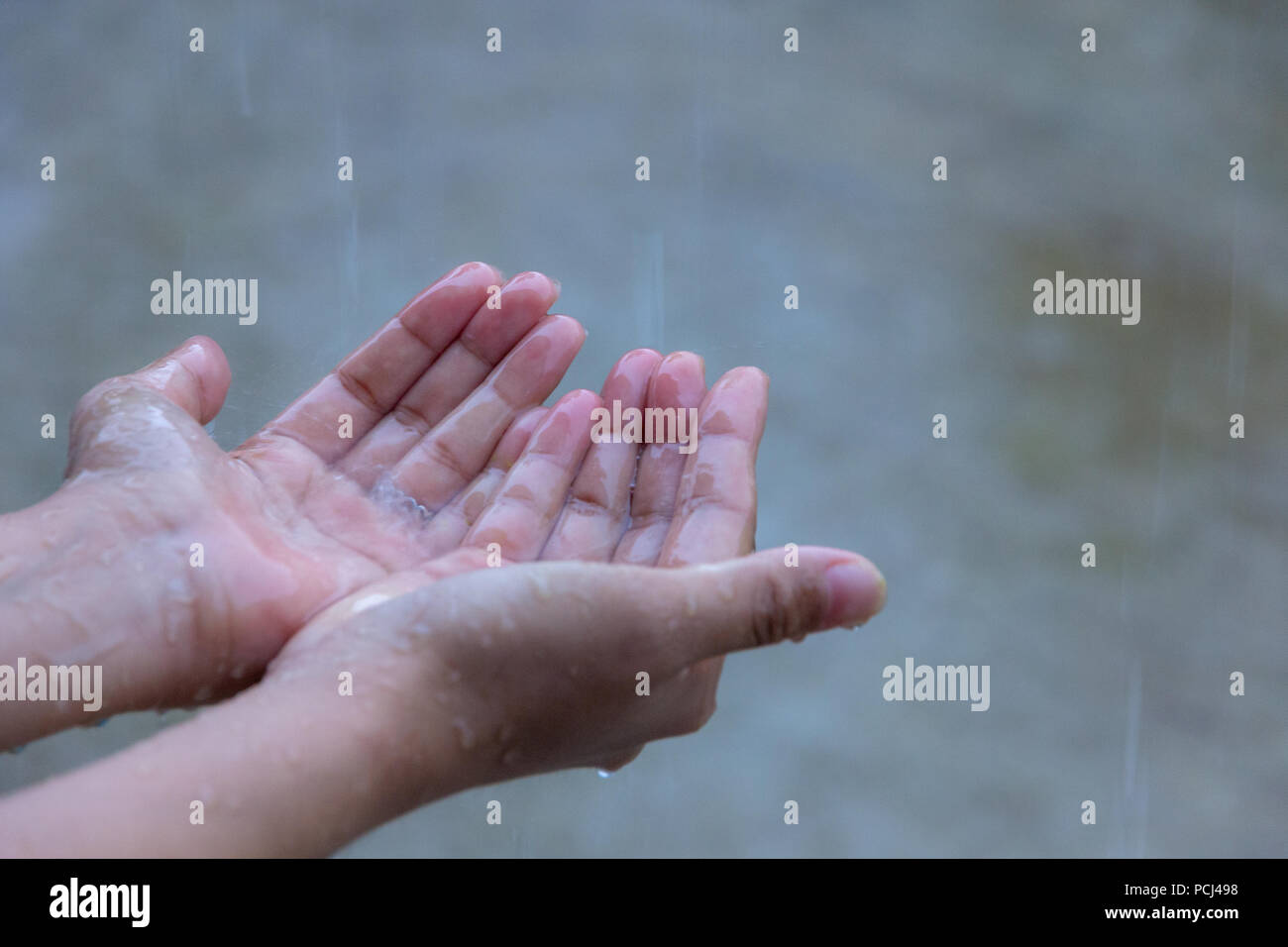 Close up of woman putting her hand in the rain catching drops of rain ...