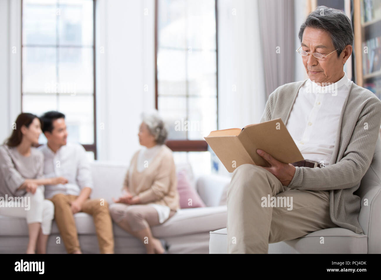Senior Chinese man reading a book at home Stock Photo - Alamy