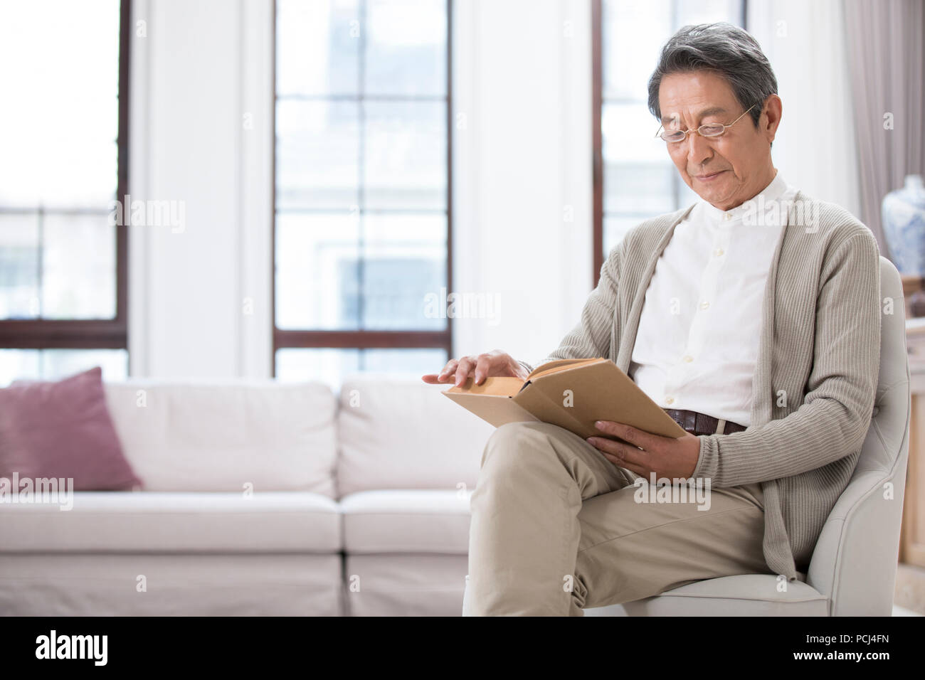 Senior Chinese man reading a book at home Stock Photo - Alamy