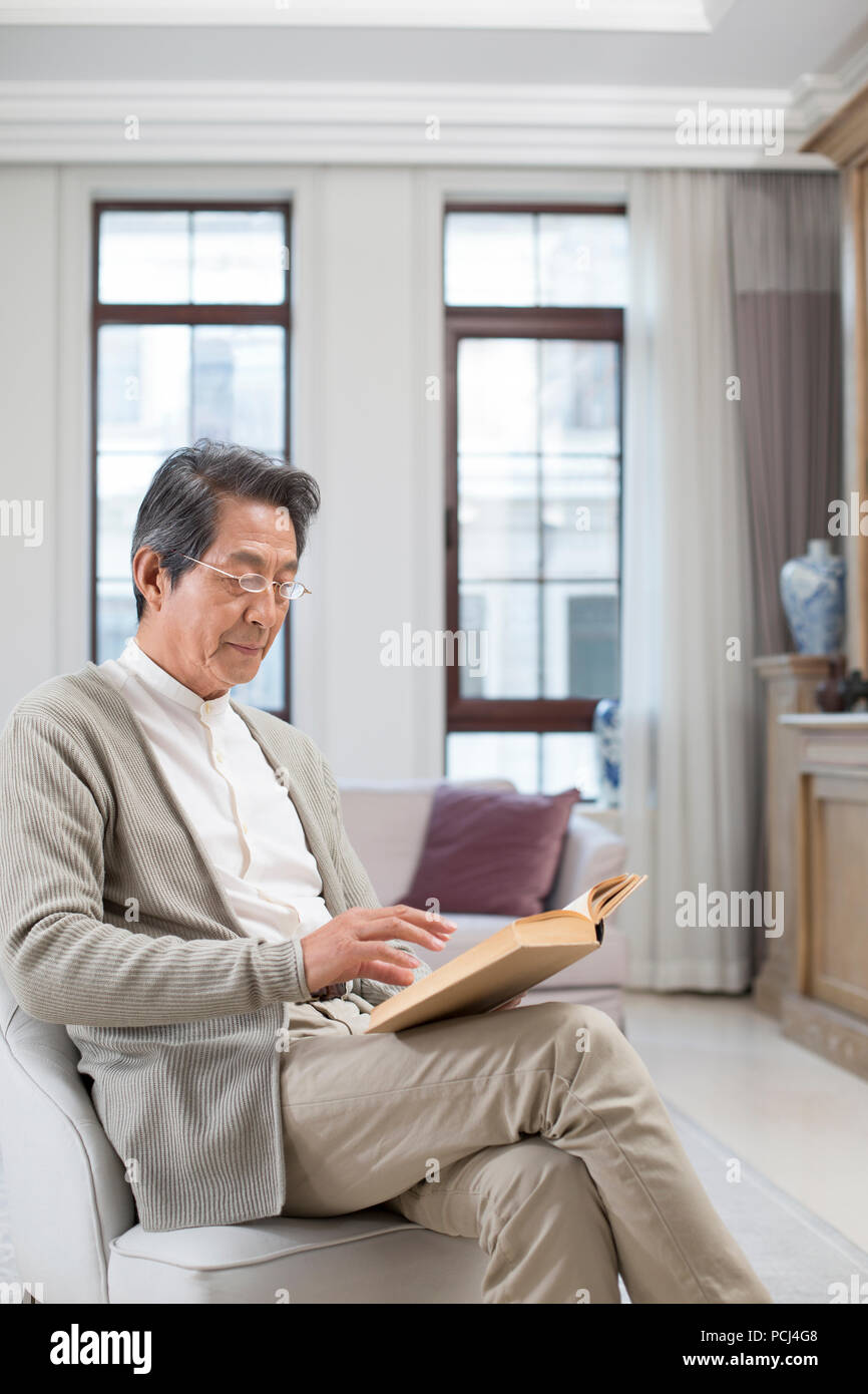 Senior Chinese man reading a book at home Stock Photo - Alamy