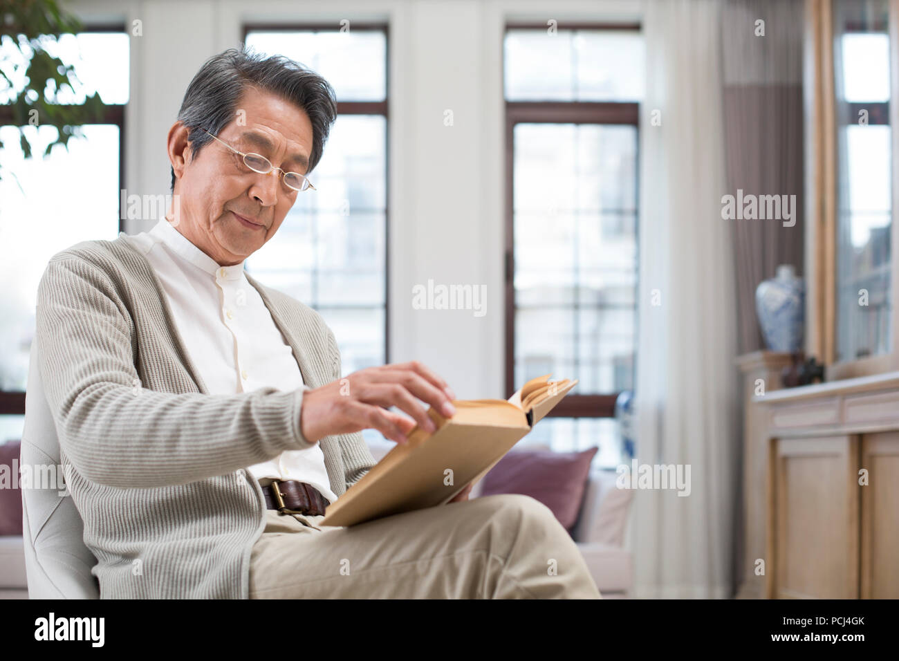 Senior Chinese man reading a book at home Stock Photo - Alamy
