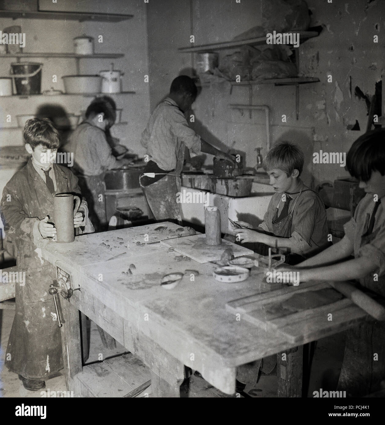 1960s, historical, schoolboys getting messy mixing clay as they take ...