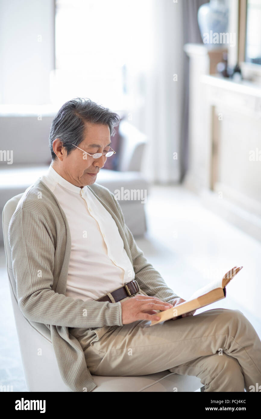 Senior Chinese man reading a book at home Stock Photo - Alamy