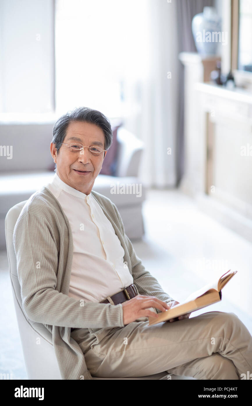 Senior Chinese man reading a book at home Stock Photo - Alamy