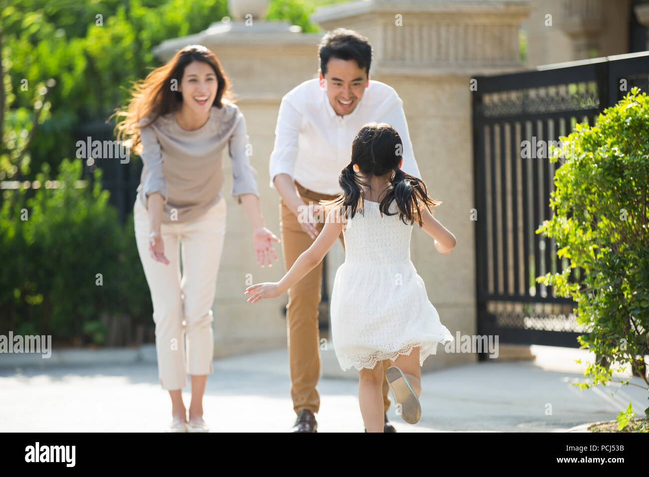 Happy little Chinese girl running towards her parents Stock Photo - Alamy