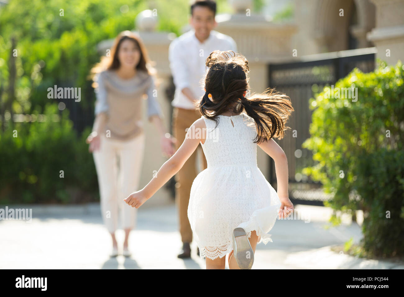 Happy little Chinese girl running towards her parents Stock Photo - Alamy