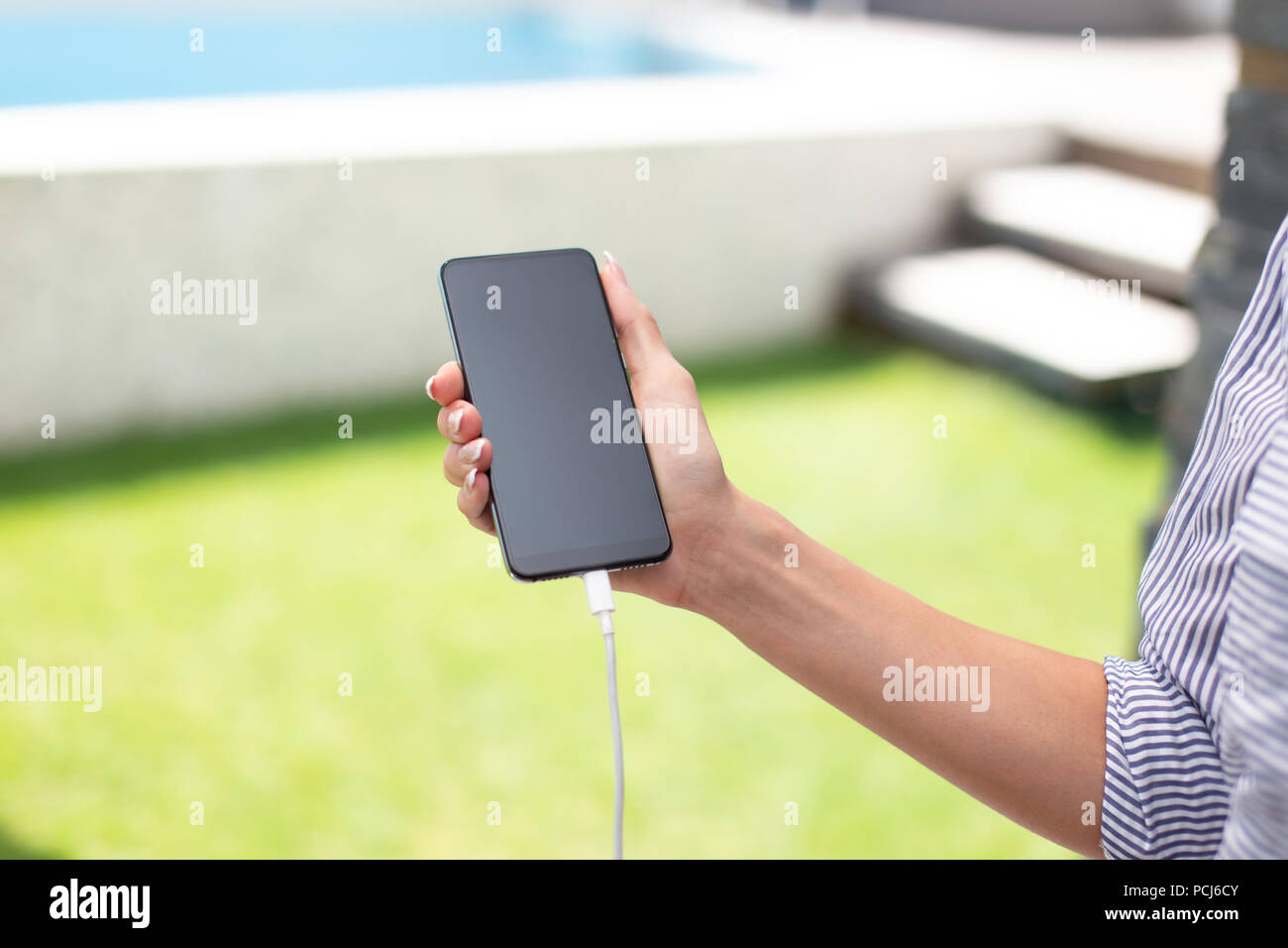 Woman hand holding smartphone while charging closeup Stock Photo - Alamy