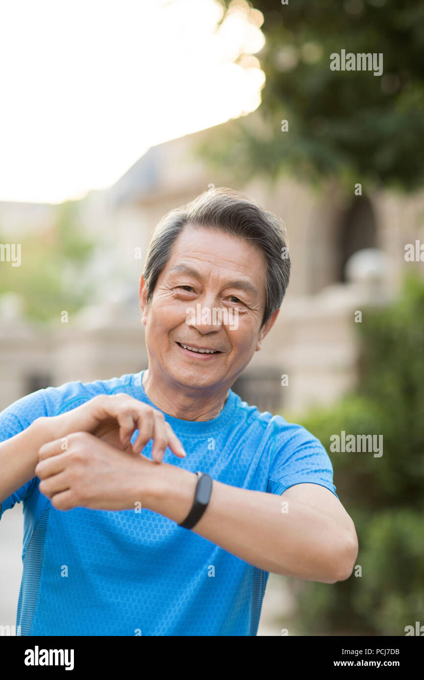 Cheerful senior Chinese man checking his smart watch Stock Photo - Alamy