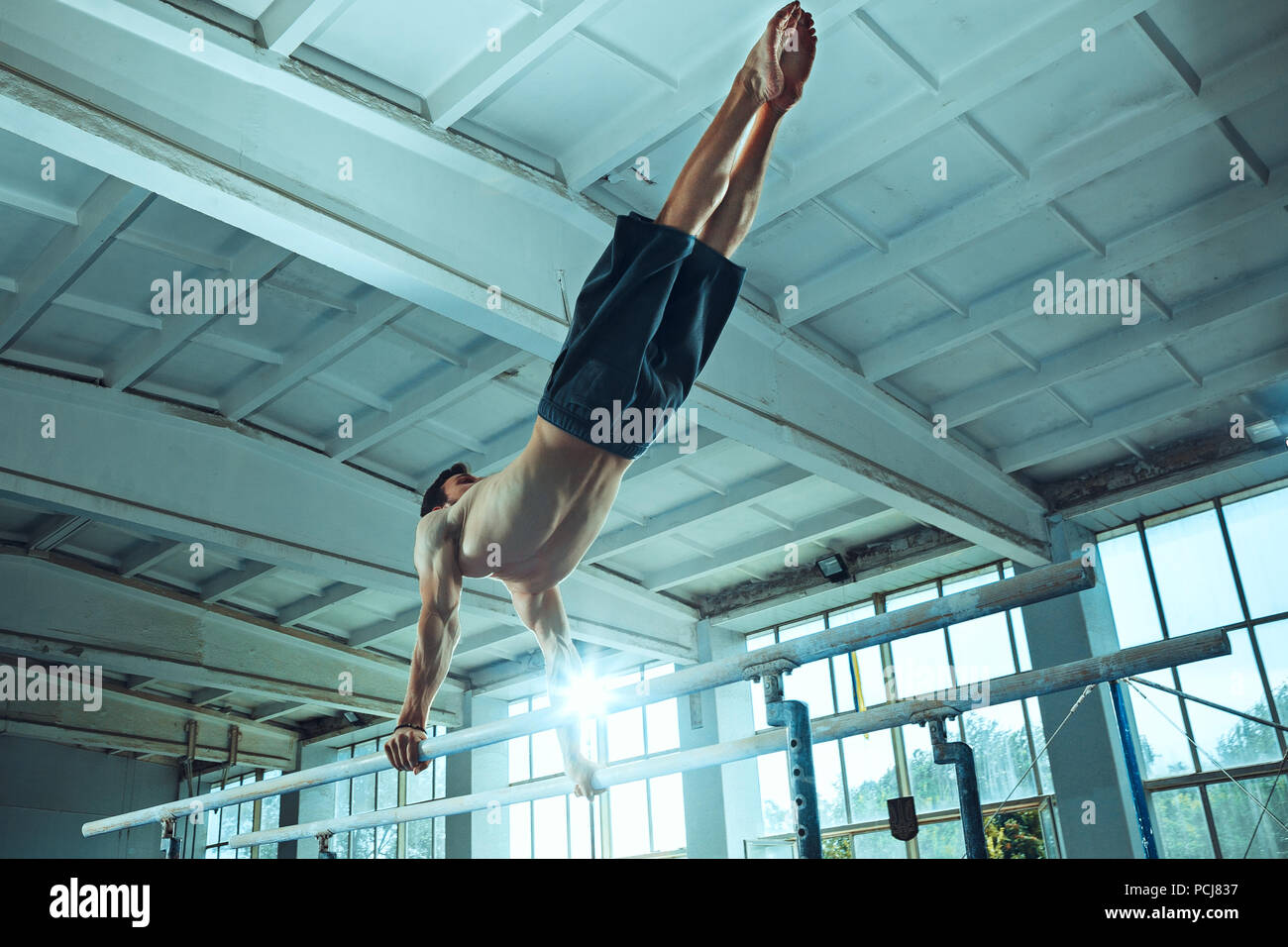 The sportsman during difficult exercise, sports gymnastics Stock Photo ...
