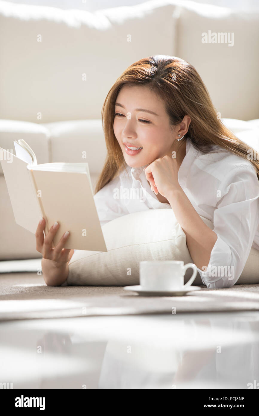 Young woman reading a book with smile on sofa hi-res stock photography ...