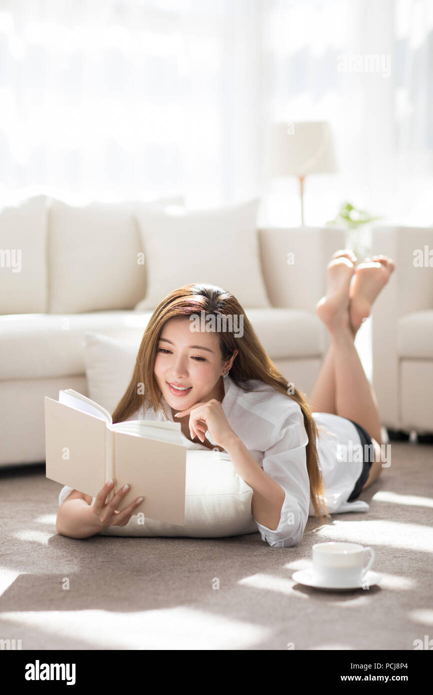 Cheerful young Chinese woman reading a book at home Stock Photo - Alamy