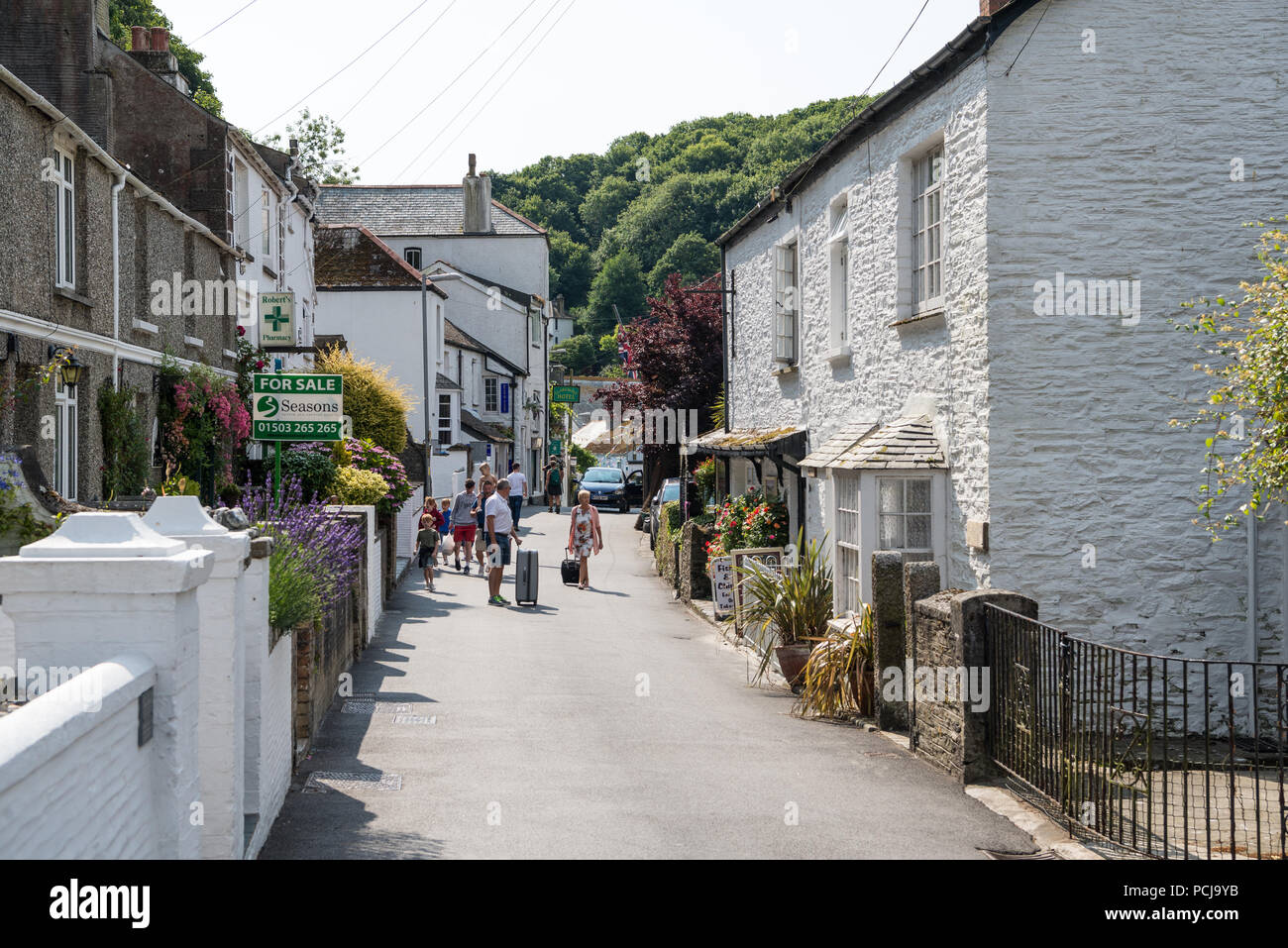 Holidaymakers walking in a narrow street of quaint cottages in Polperro ...