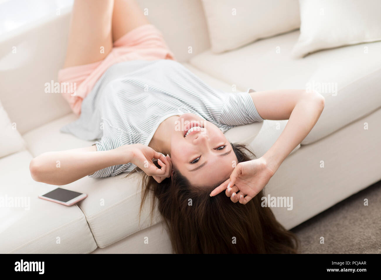 Cheerful young Chinese woman relaxing on sofa Stock Photo - Alamy