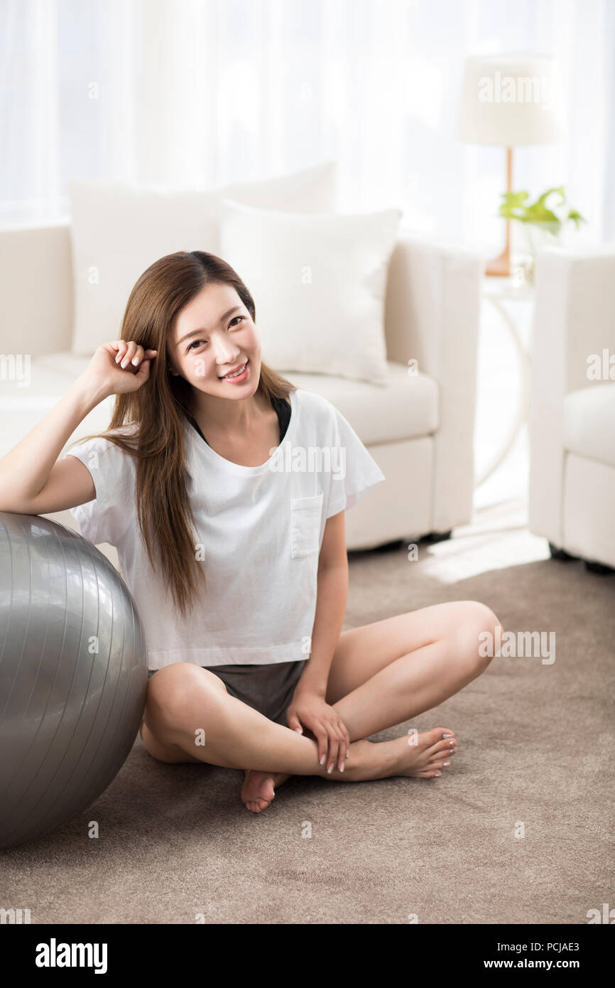 Cheerful young Chinese woman leaning on fitness ball Stock Photo - Alamy