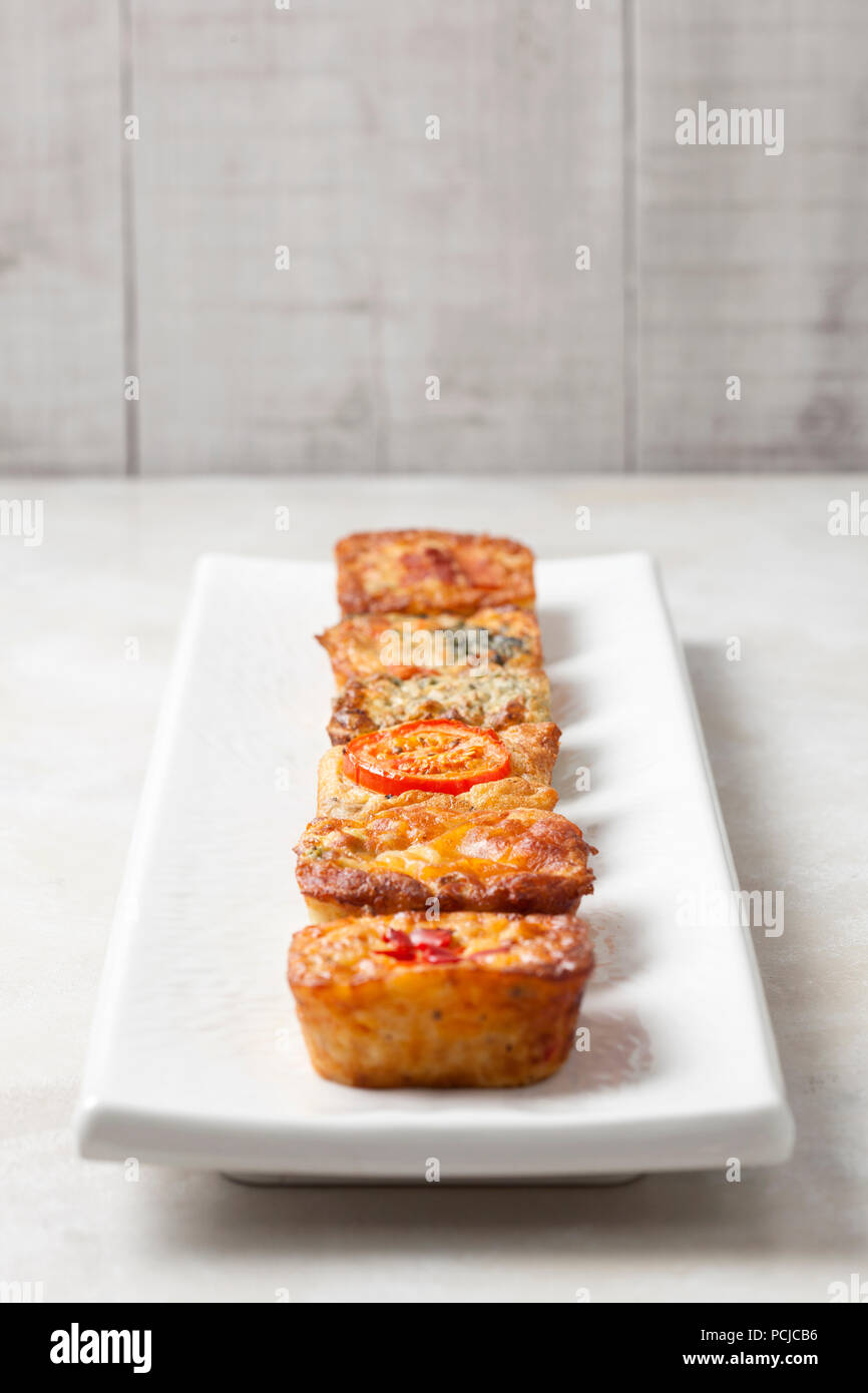 Five individual mini quiches on a white rectangular plate Stock Photo ...