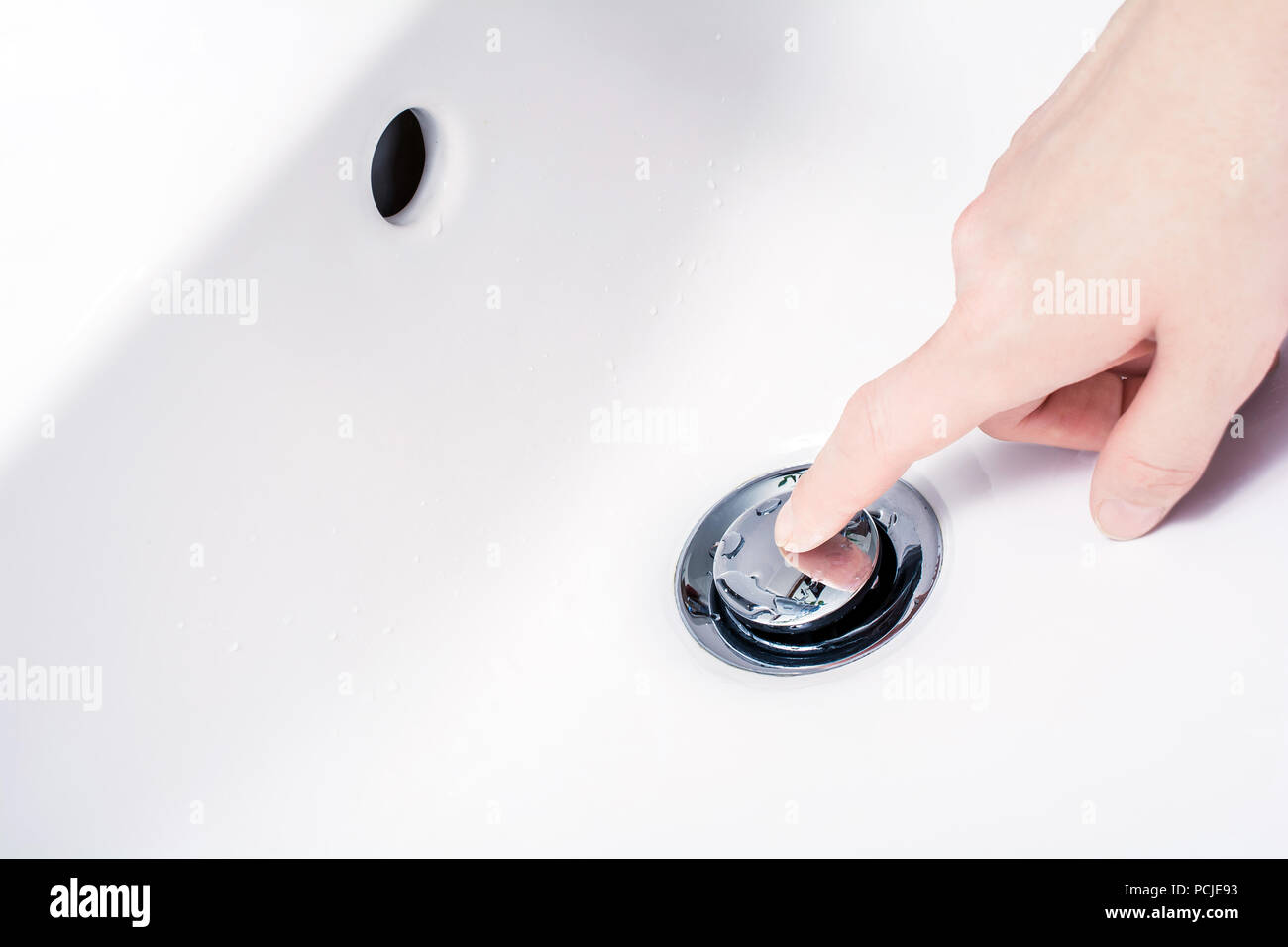 Female Hand With Finger On An Open, Pop-Up Drain Plug, Ready To Press ...