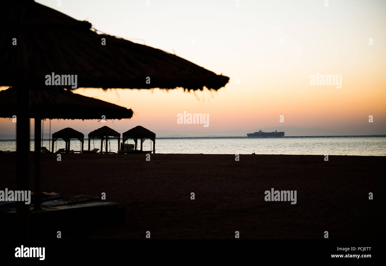 cargo ship at sea horizon through sunrise beach Stock Photo - Alamy