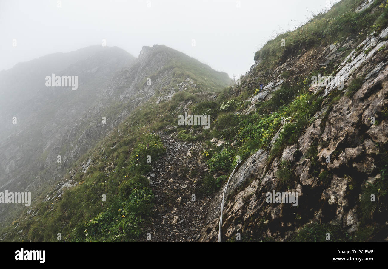 scary hiking path covered in fog on the ridge of a mountain in the ...