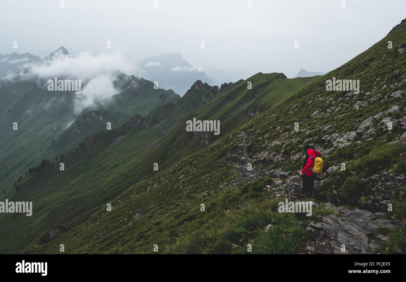 two people walking up a steep mountain hiking path covered in fog and ...