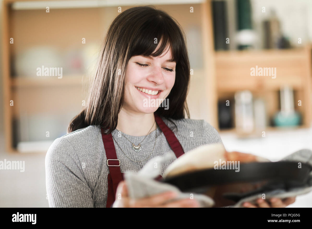 Smiling Woman standing in the kitchen holding a freshly baked loaf of ...