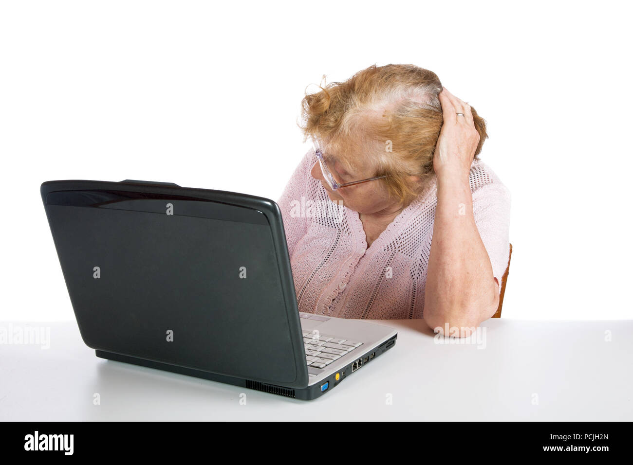 The old woman in glasses looks at the screen notebook on a white ...