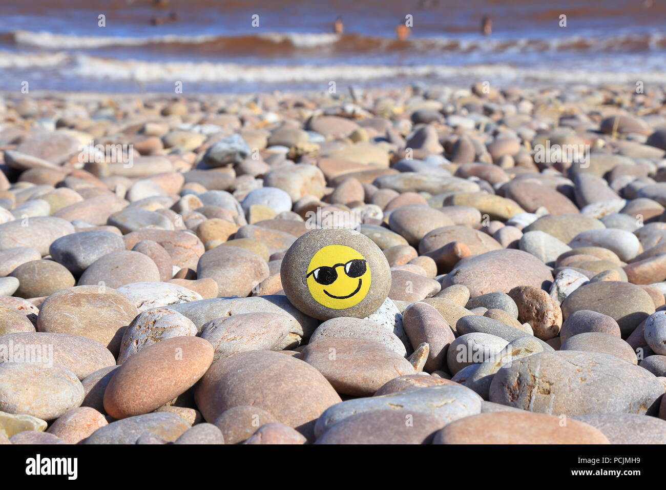 Stone with painted smiley face on the pebble beach of the Jurassic ...