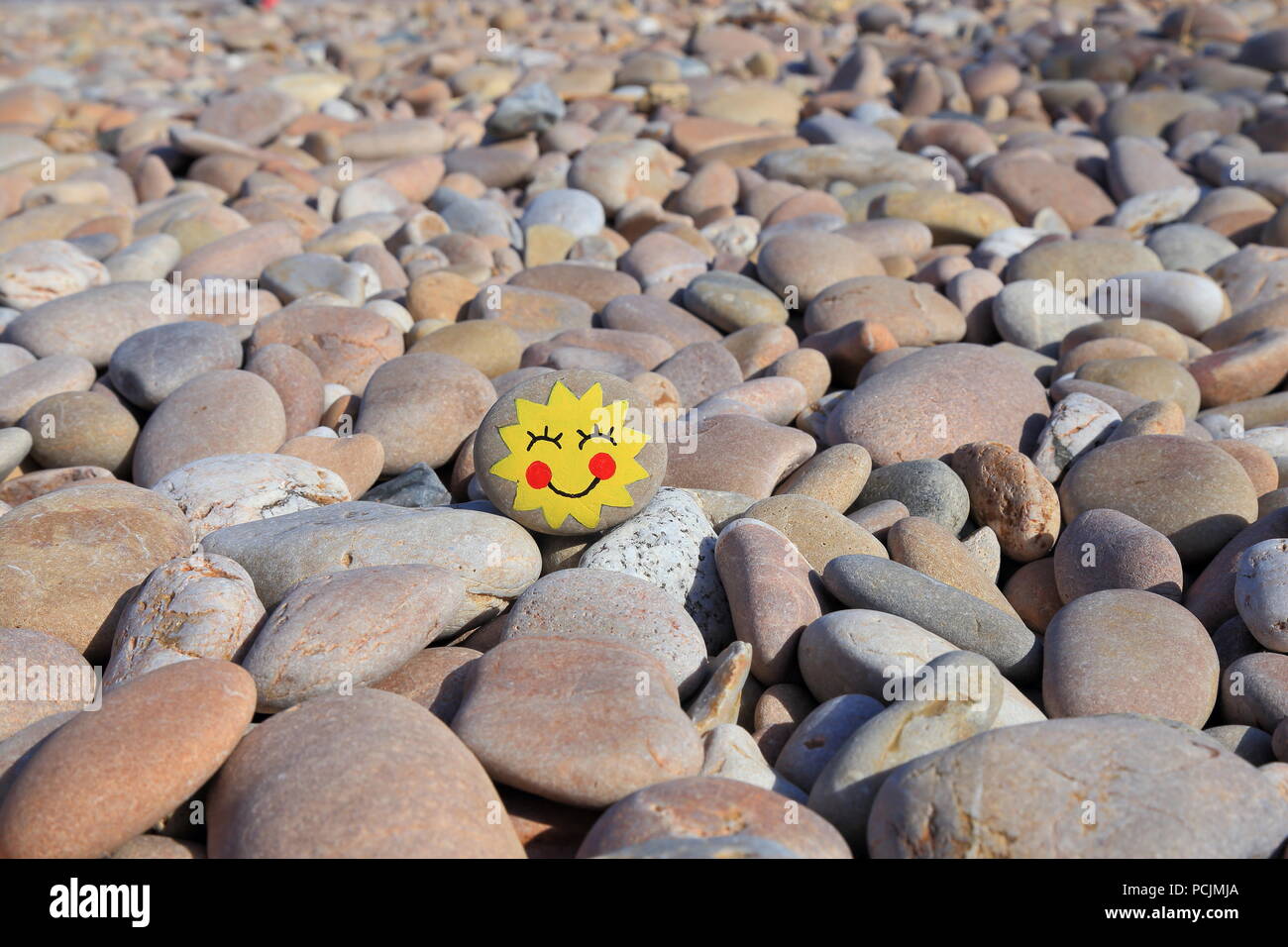 Stone with painted smiley face on the pebble beach of the Jurassic ...