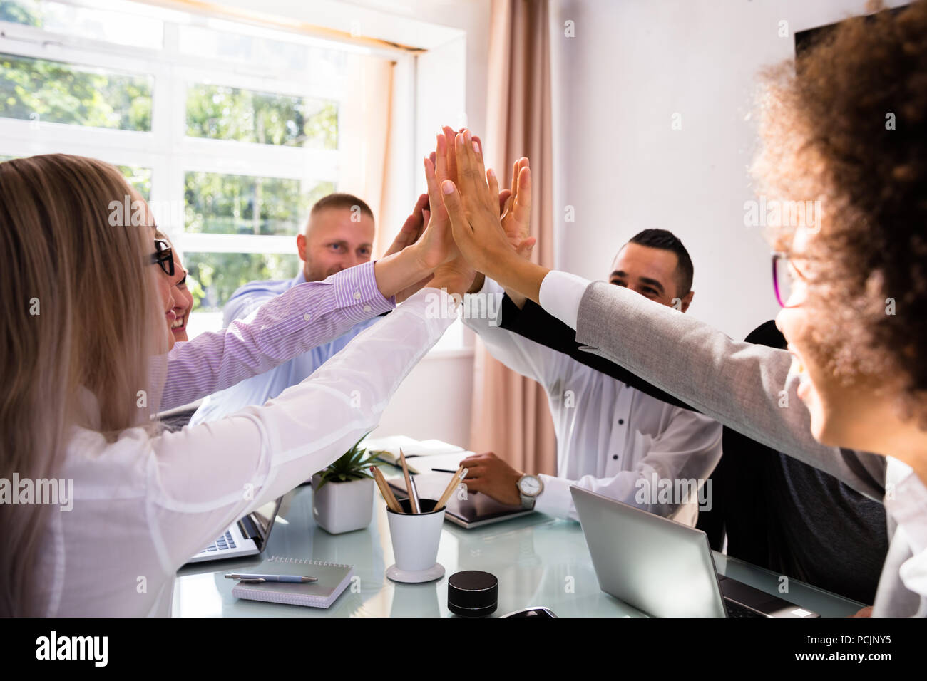 Group Of Businesspeople Giving High Five Over Desk At Workplace Stock ...
