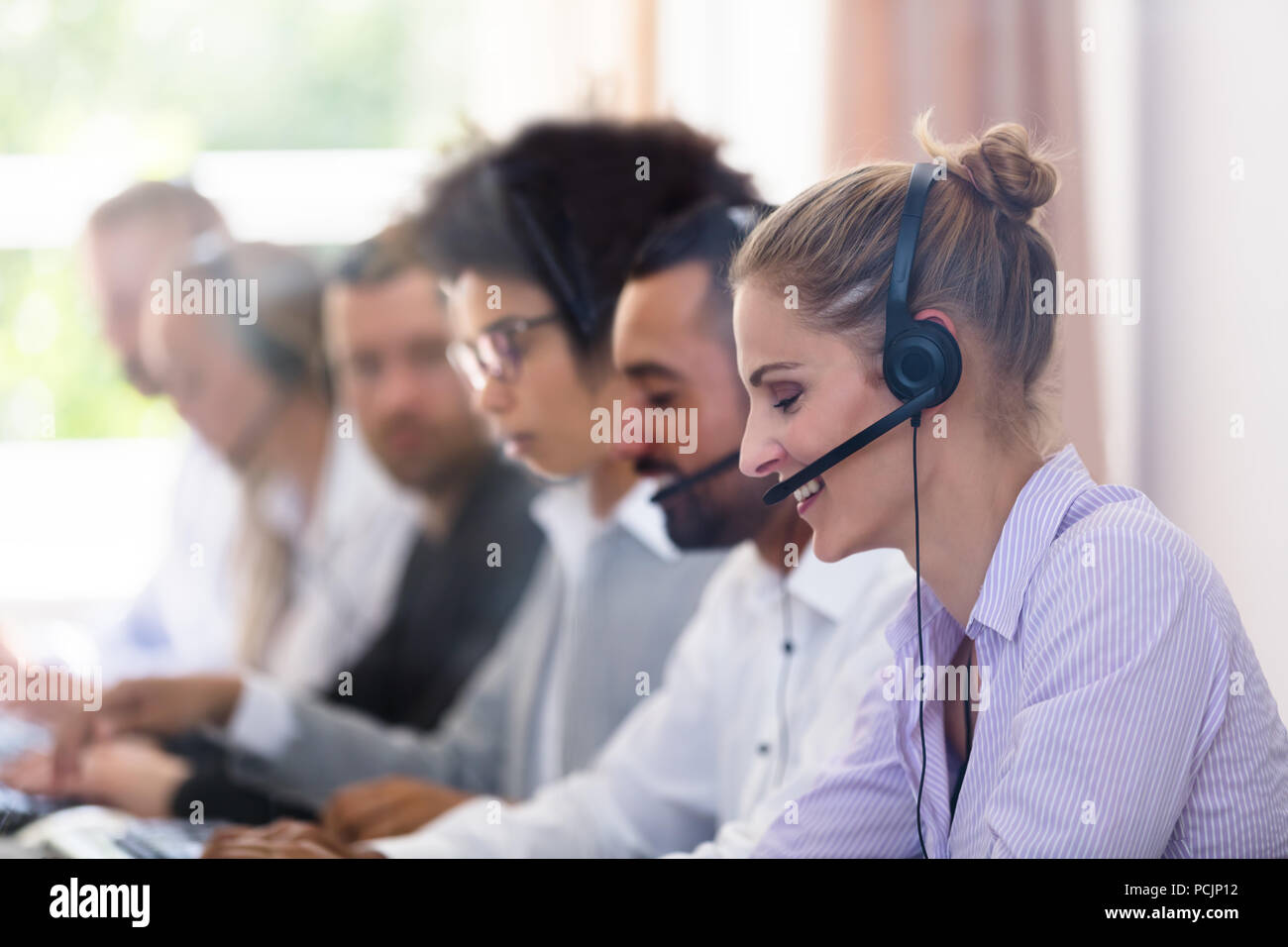 Young Customer Service Executives Using Earphones Working In Call ...