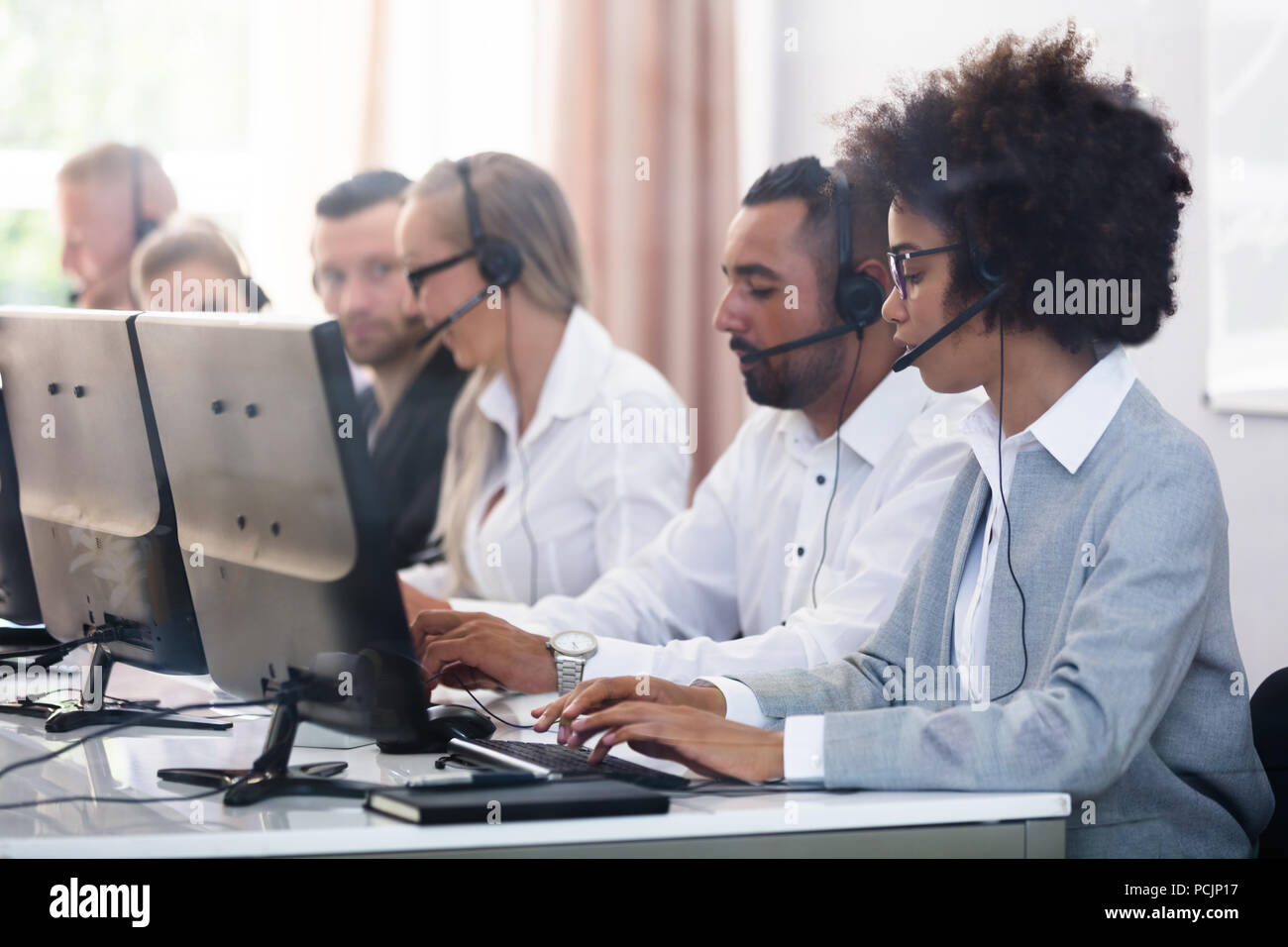 Young Customer Service Executives Using Earphones Working In Call ...
