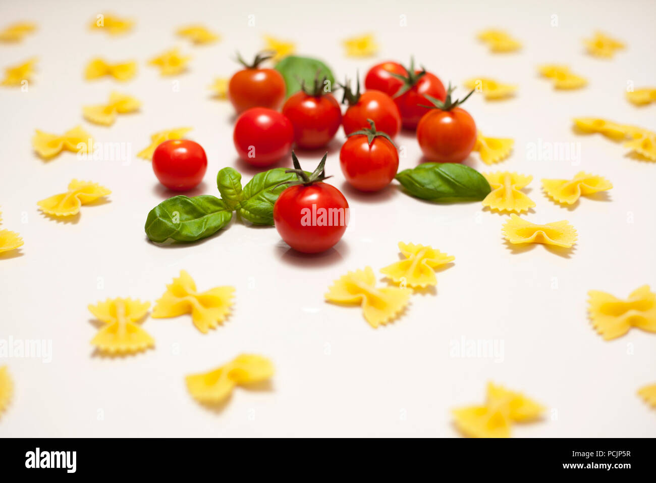 Isolated fresh red and orange cherry tomatoes with green leafs of basil ...