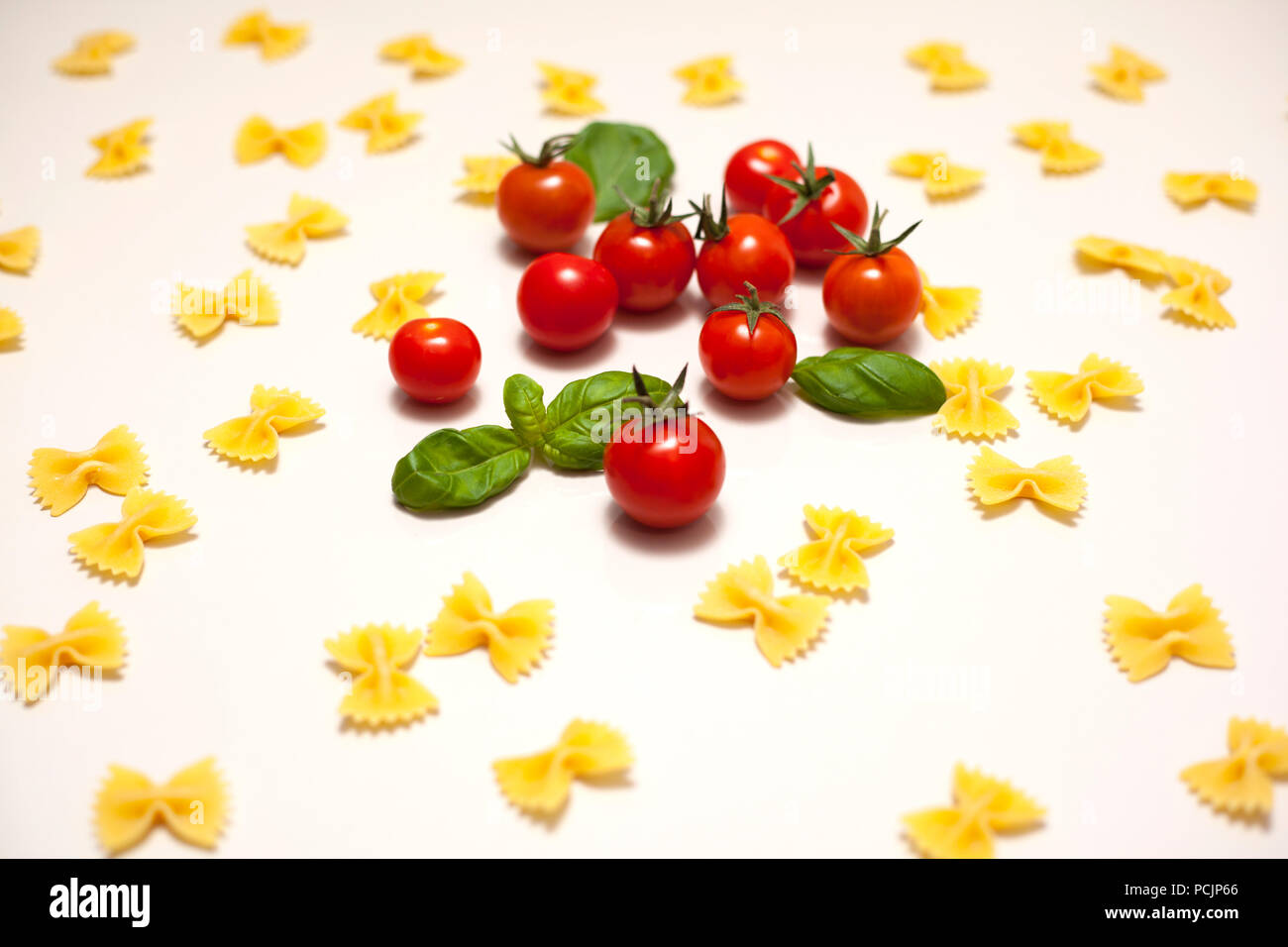 Isolated fresh red and orange cherry tomatoes with green leafs of basil ...