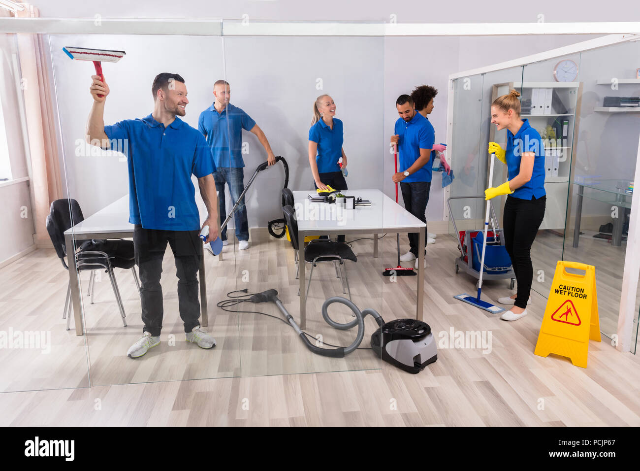 Group Of Skilled Young Janitors In Uniform Cleaning Office Stock Photo ...